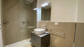 Quarto Individual Deluxe | Casa de banho | Um polibã, um chuveiro fixo, um secador de cabelo, um bidé