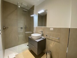 Quarto Individual Deluxe | Casa de banho | Um polibã, um chuveiro fixo, um secador de cabelo, um bidé 