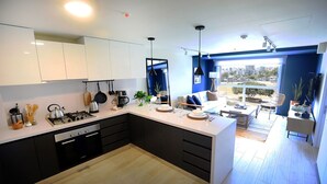 Cozinha moderna com armários brancos, uma ilha central e área de refeições com vista para a cidade.
