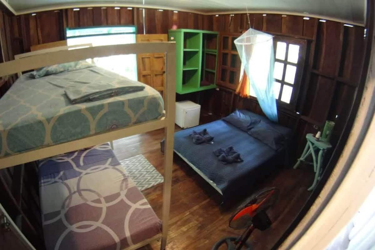 Quarto com beliche, um armário verde, uma bicicleta e uma janela com cortinas.