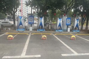 Área de estacionamento com estações de carregamento para veículos elétricos e código QR para pagamento.
