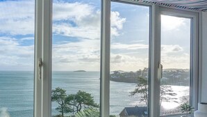 Quarto com uma grande janela que dá para a vista da costa, incluindo o mar e uma ilha distante.