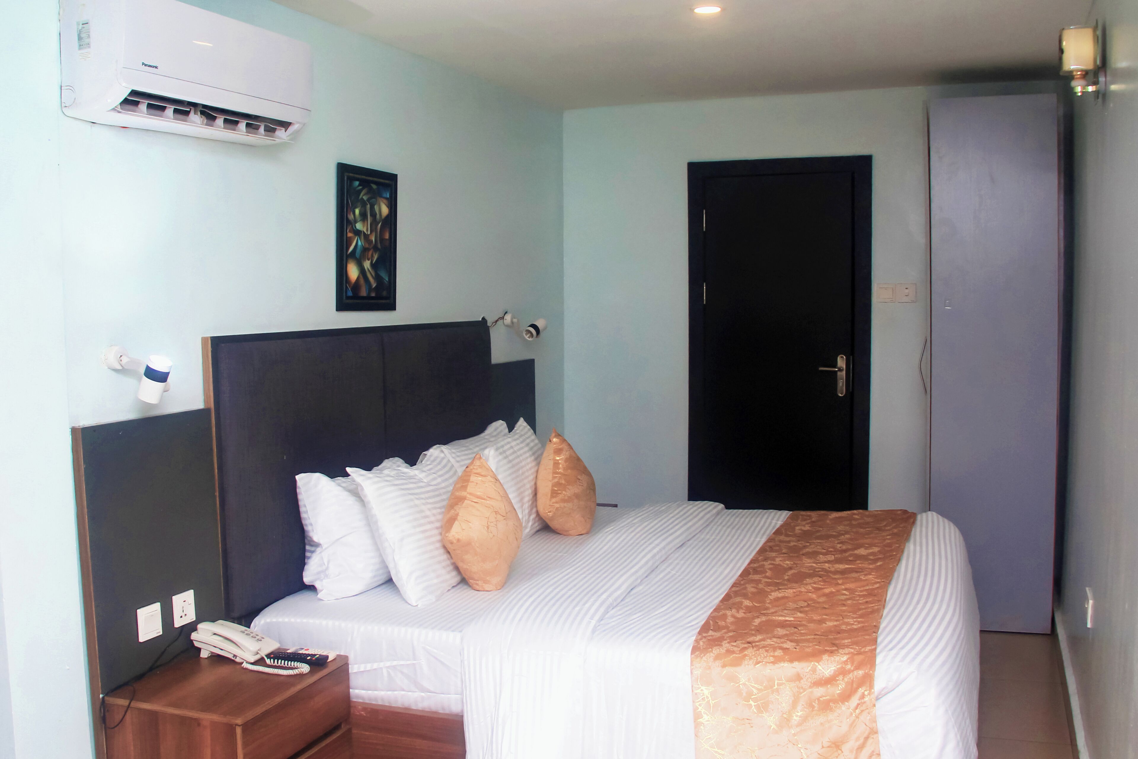 Quarto de hotel com cama, mesa de cabeceira e ar condicionado.
