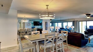 Uma sala de estar ampla, com uma mesa de jantar e cadeiras, um sofá e um ventilador de teto.
