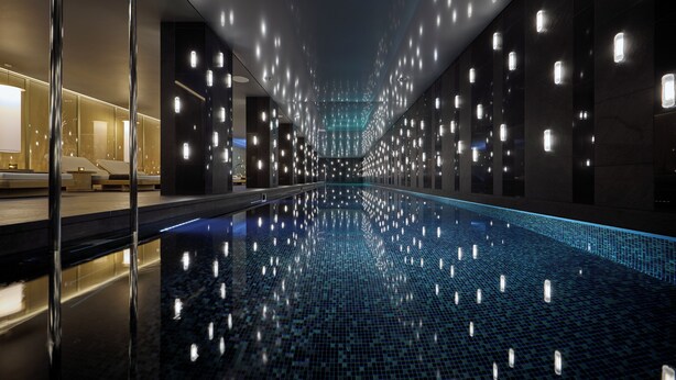 Uma piscina interior moderna com piso espelhado e luzes uniformemente distribuídas no teto.