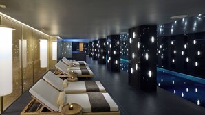 Uma área de spa com espreguiçadeiras, piscina e iluminação ambiente.