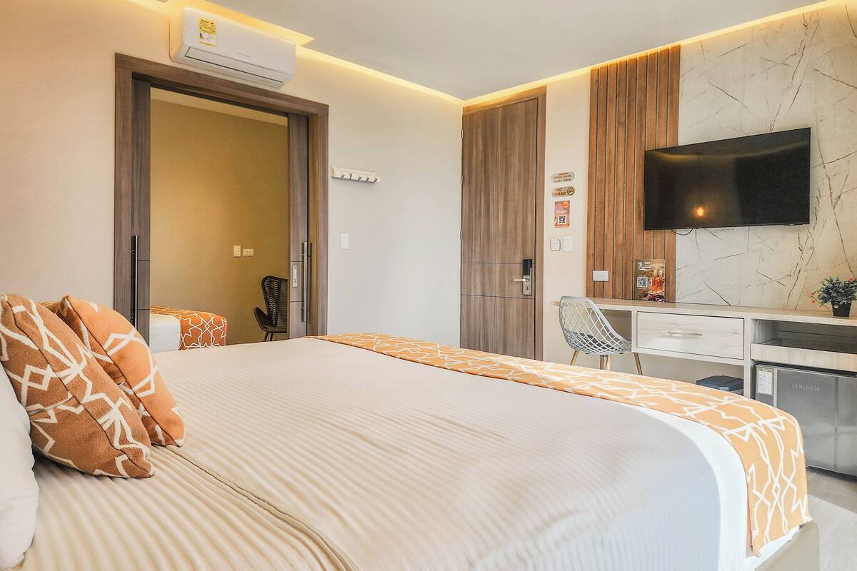 Quarto de hotel moderno com uma cama grande, uma mesa, uma cadeira e uma televisão.