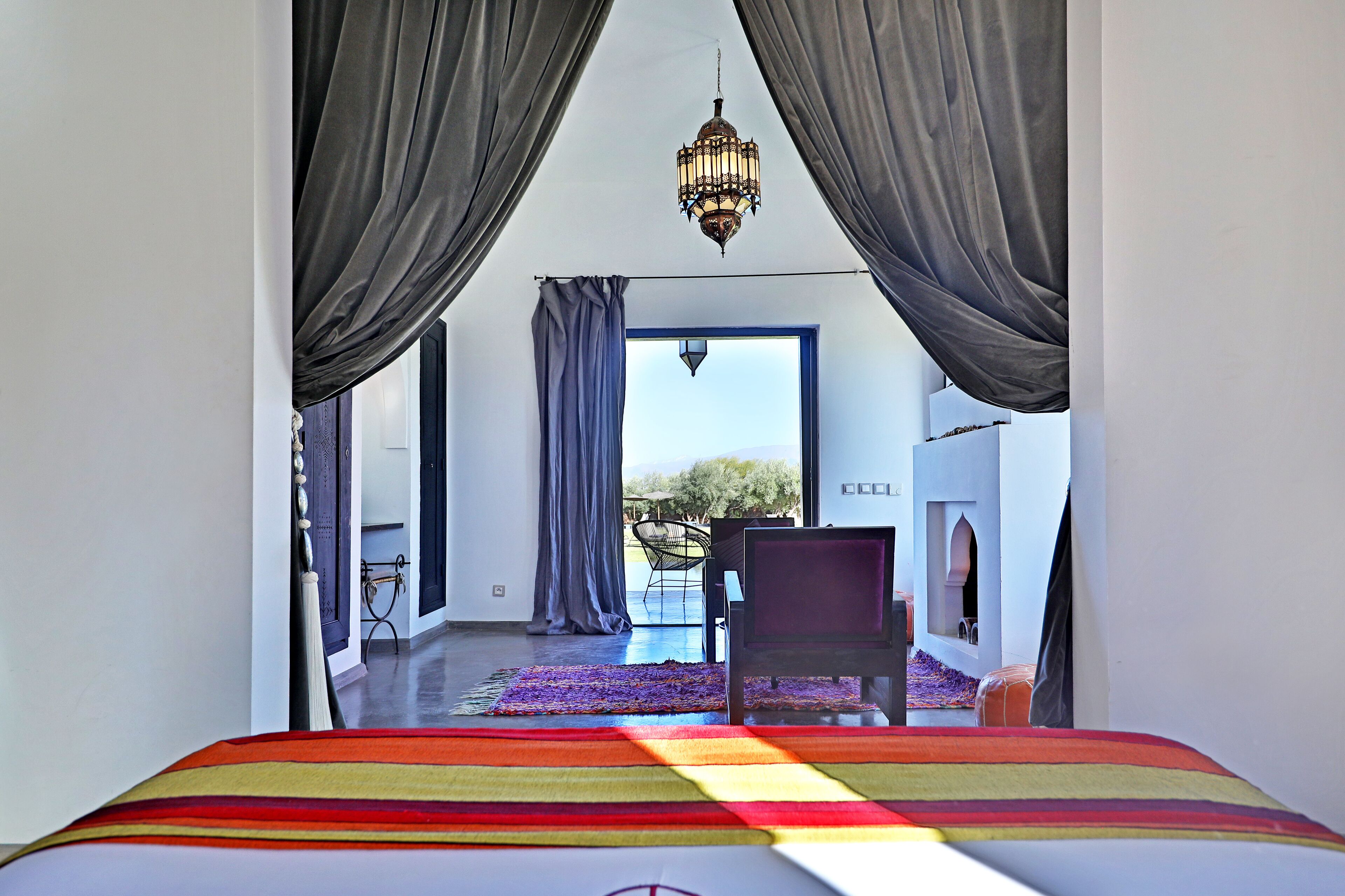 Quarto com cama, cadeira e vista para o exterior.