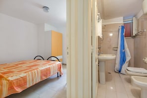 Quarto com cama, guarda-roupa e banheiro com pia e vaso sanitário.
