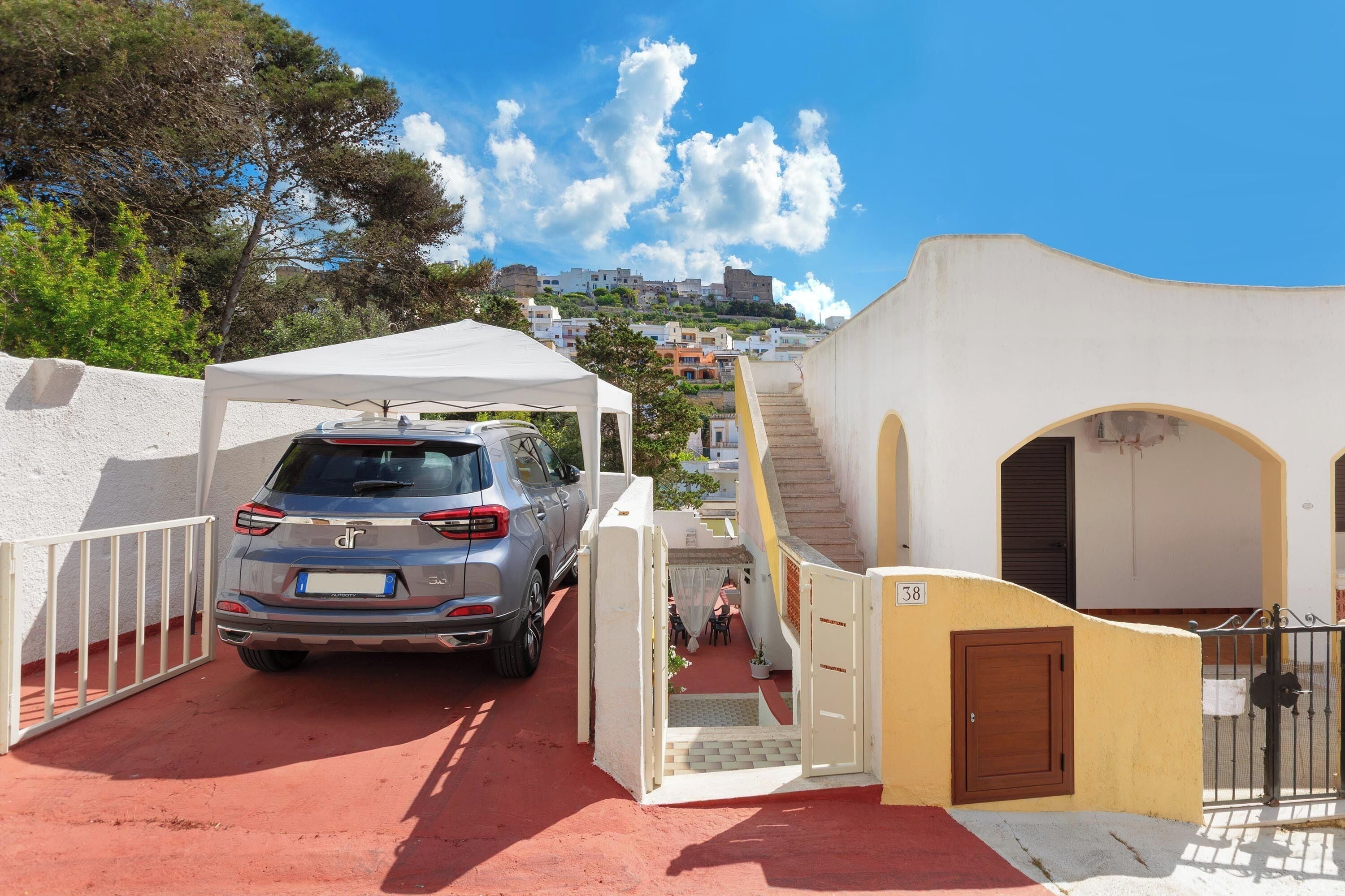 Carro estacionado em uma entrada coberta com uma escadaria que leva a um edifício.