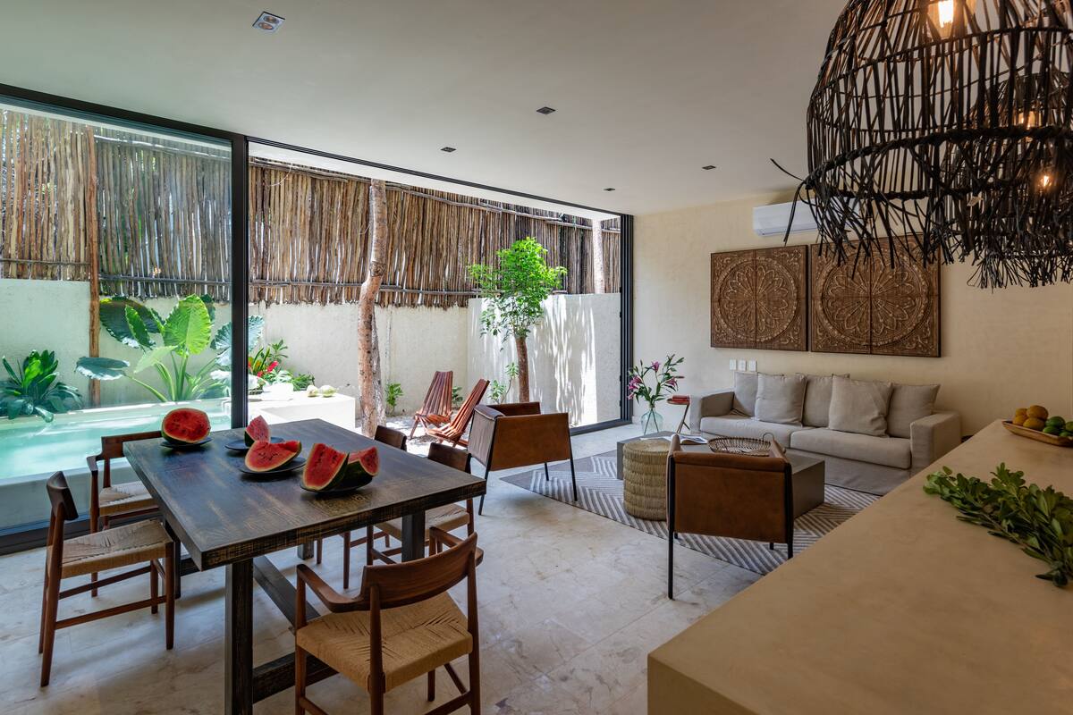 Uma sala de estar moderna com área de jantar, janelas amplas e luminária pendente.