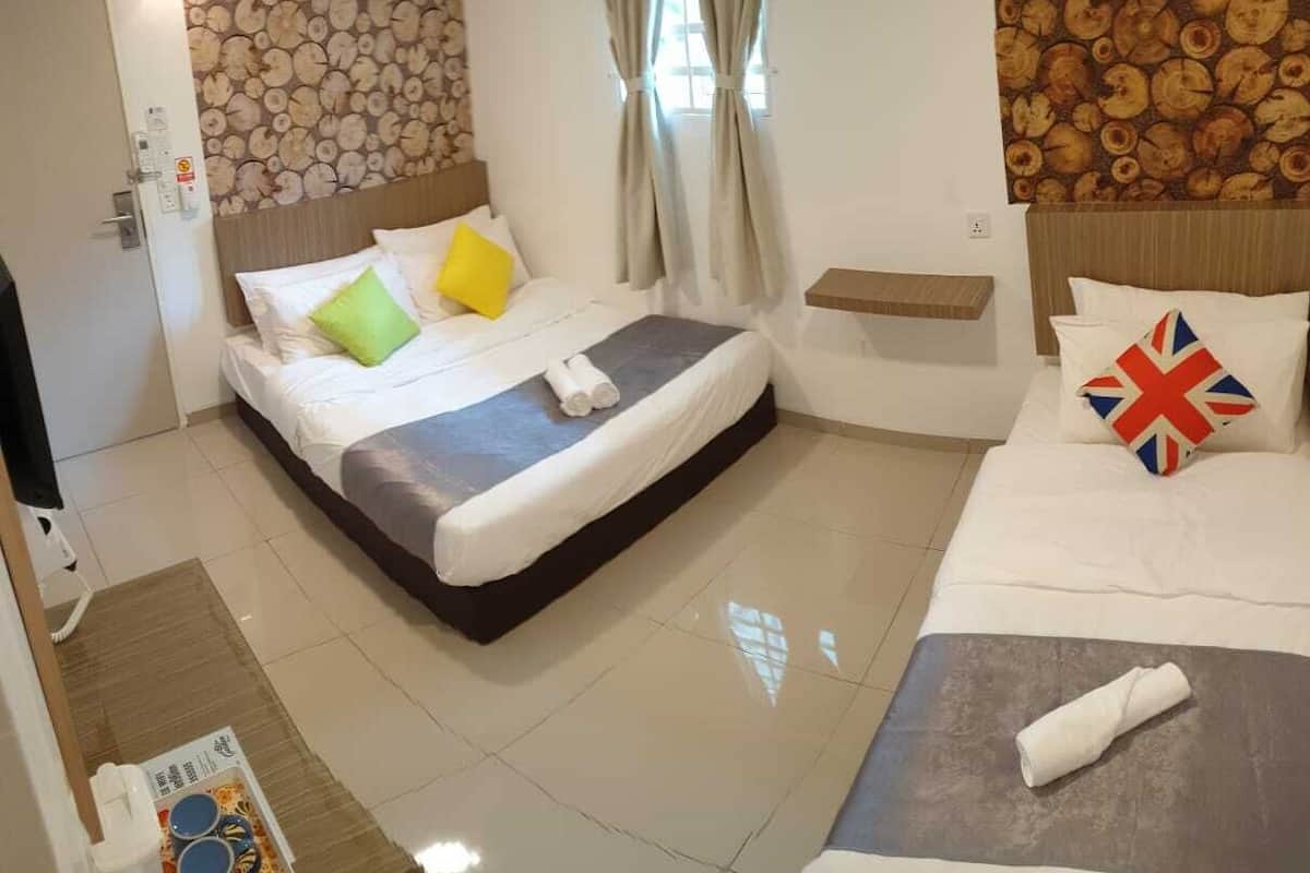 Quarto de hotel com cama, mesa de cabeceira, escrivaninha pequena e janela com cortinas.