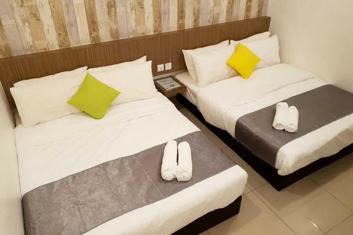 Duas camas lado a lado com roupa de cama branca, cabeceira de madeira, manta cinza e travesseiro amarelo.
