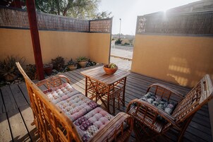 Um deck de madeira com móveis de vime e plantas em vasos.