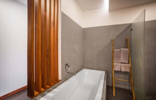 Uma casa de banho moderna com uma banheira grande, um divisório de painel de madeira e um compartimento de chuveiro em vidro.