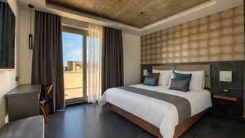 Quarto de hotel moderno com uma cama grande, uma escrivaninha e uma cadeira.