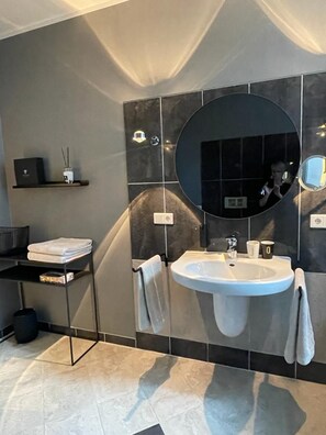 Casa de banho moderna com um espelho grande, uma pia e um porta-toalhas.