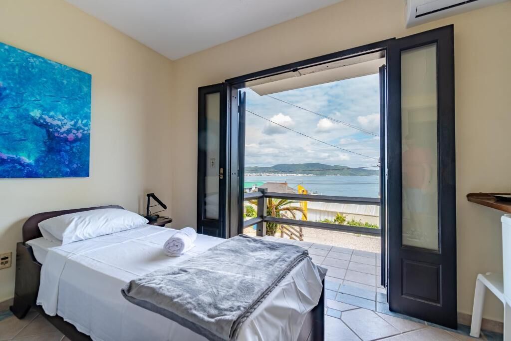 Quarto com cama, quadro e varanda com vista para o mar.