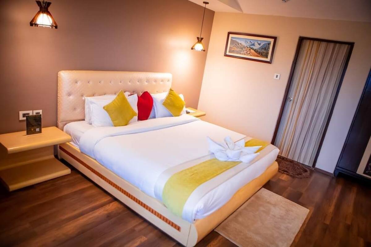 Cama bem arrumada com cabeceira branca, mesa de cabeceira e criado-mudo.