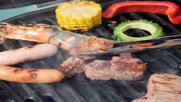 Uma churrasqueira com diversos tipos de carne e legumes sendo preparados.