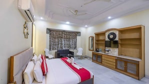 Quarto de hotel com cama, escrivaninha, televisão e guarda-roupa.