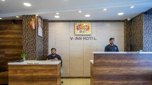 Um balcão de recepção com uma placa indicando "V-inn Hotel" e um quadro emoldurado acima.