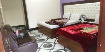 Quarto com duas camas, um sofá e uma mesinha.