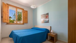 Quarto com cama, mesa de cabeceira, janela com persianas de madeira e quadro na parede.