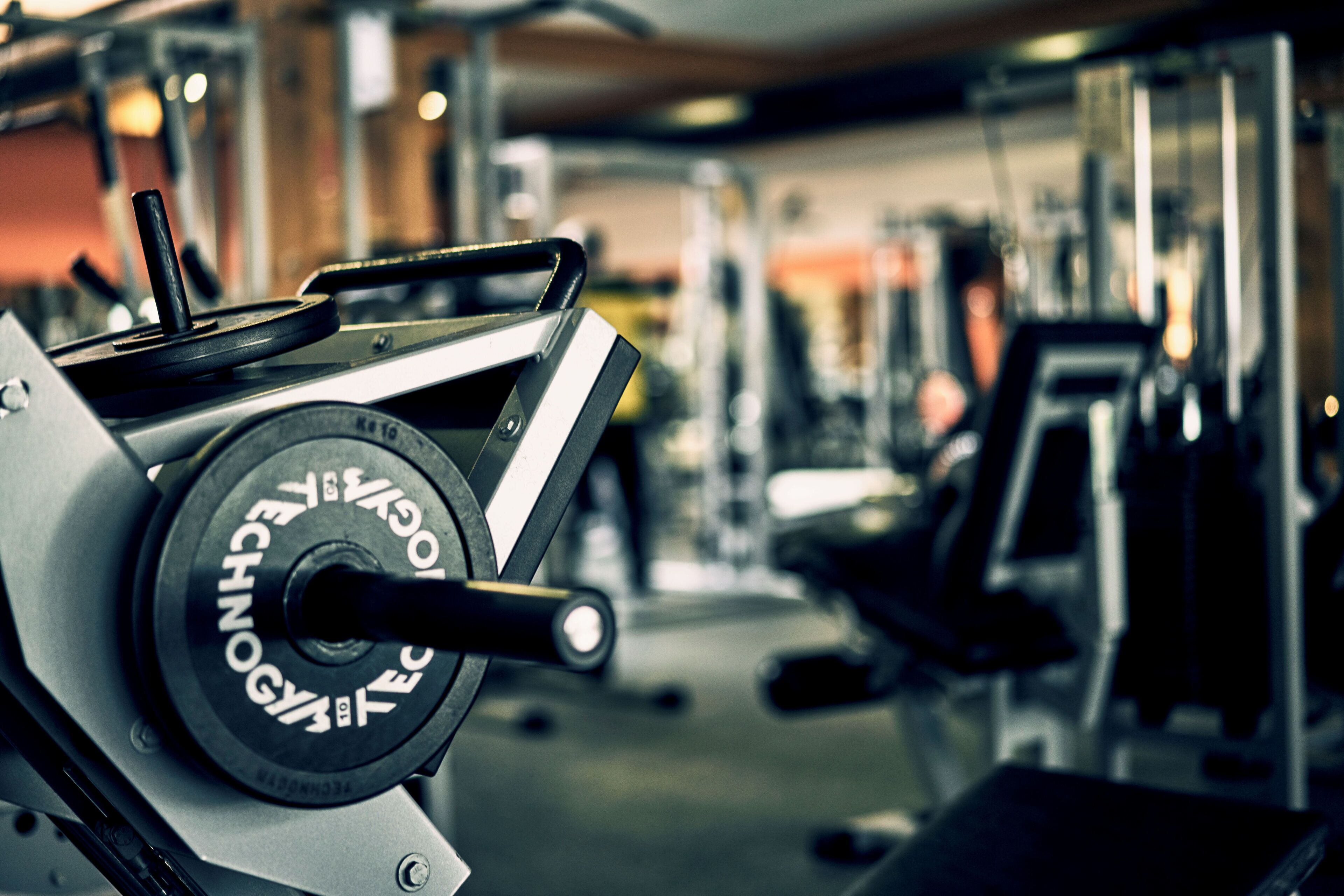 Uma academia com diversos equipamentos de exercícios, incluindo uma torre de pesos e um banco.