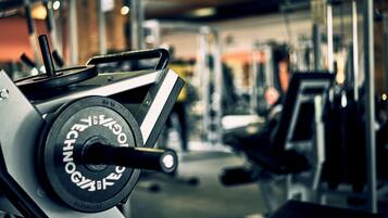 Uma academia com diversos equipamentos de exercícios, incluindo uma torre de pesos e um banco.