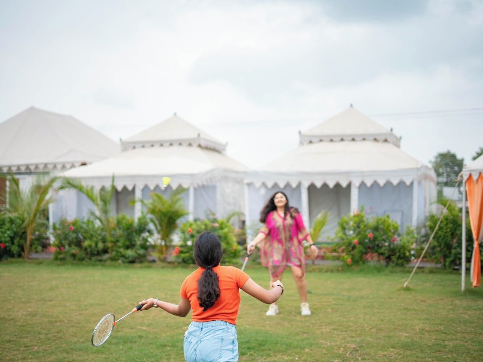 Ambiente externo com uma estrutura de tenda e uma pessoa jogando badminton.
