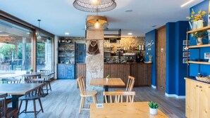 Um restaurante com mesas e cadeiras de madeira, área de bar e um pilar de pedra.