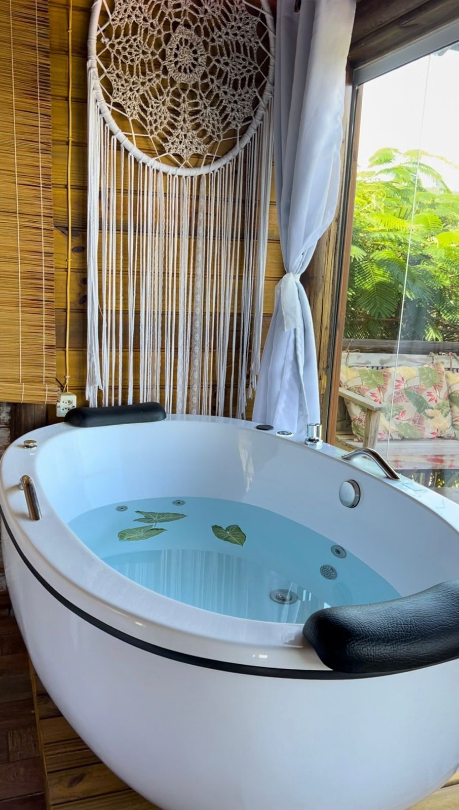 Uma banheira de hidromassagem com vista desobstruída do entorno, incluindo um painel de macramé e uma janela com vista para o verde lá fora.