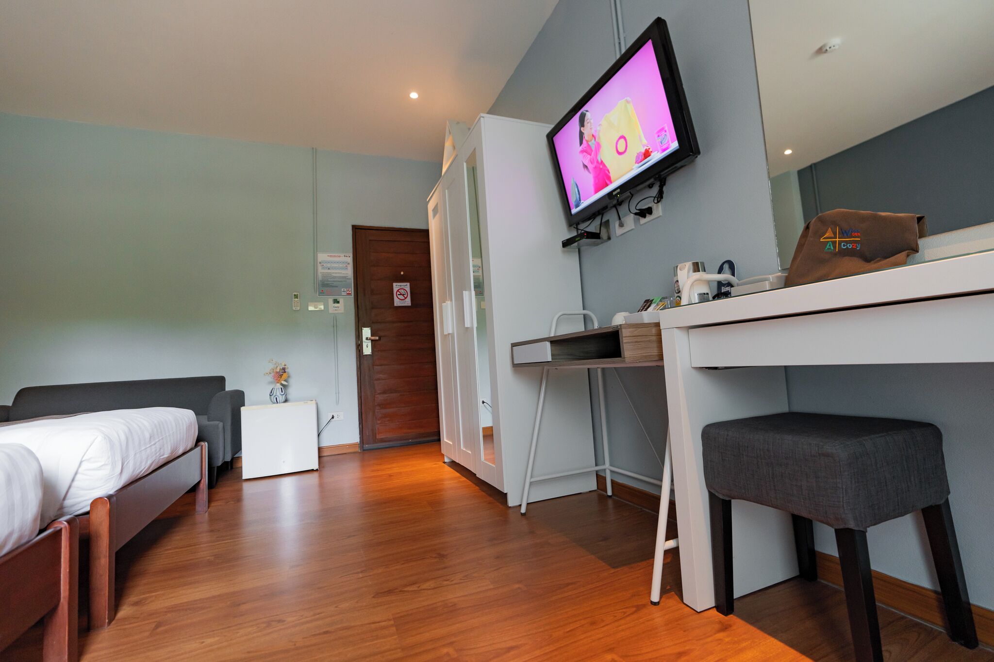 Quarto de hotel moderno com cama, escrivaninha, cadeira, televisão e uma pequena mesa com uma toalha.