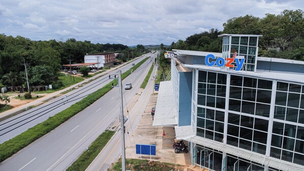 Um hotel moderno com um destaque para a placa 'Cozy', fachada de vidro e telhado plano.