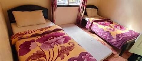Quarto com duas camas, cada uma com roupa de cama estampada, uma janela com cortinas e um tapete estampado.