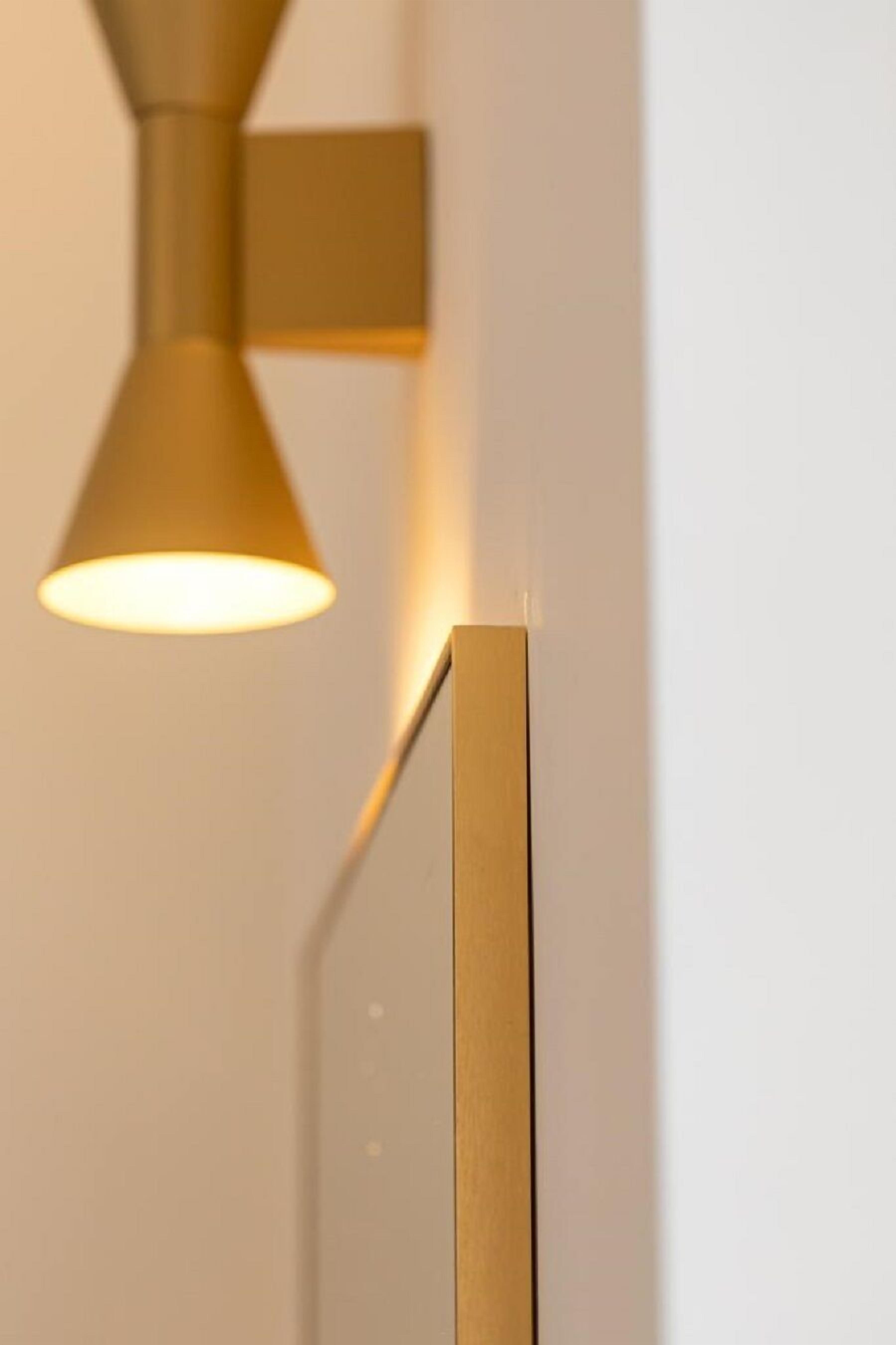 Uma luminária moderna, fixada na parede, com acabamento metálico elegante.