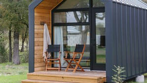Uma cabana moderna com um deck de madeira e duas cadeiras.