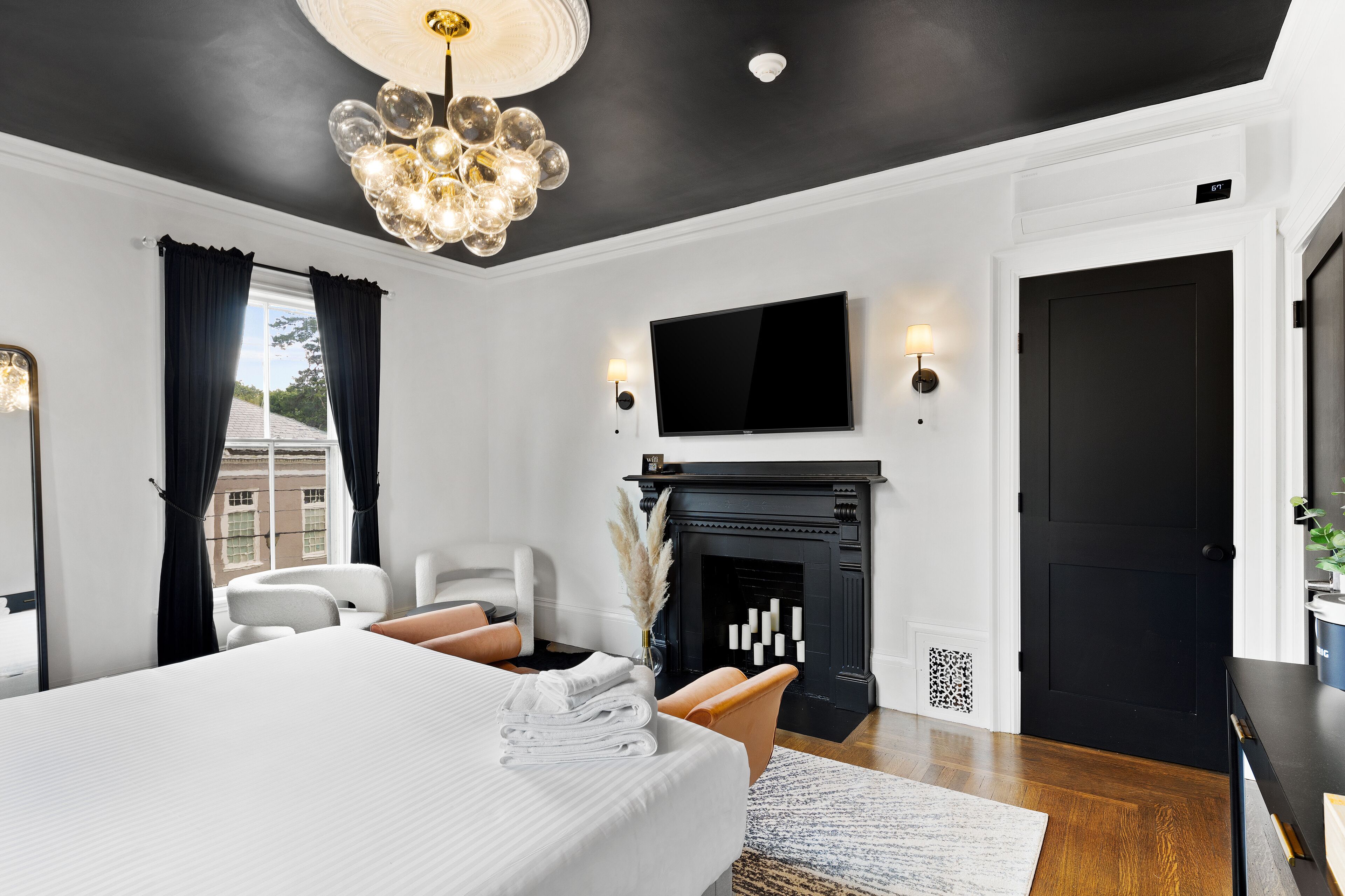 Quarto de hotel moderno com uma cama grande, lareira, TV de tela plana e vista para o exterior.