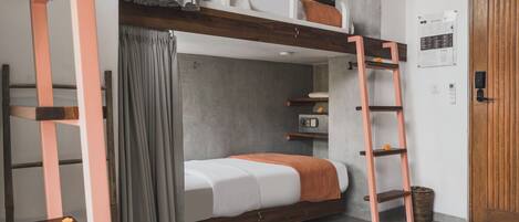 Uma cama de beliche com escada, uma mesinha e uma porta com tranca.