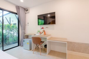 Quarto moderno com escrivaninha, cadeira e televisão de tela plana fixada na parede.