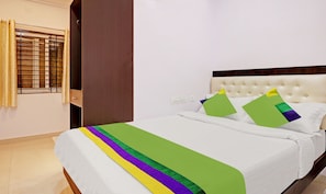 Quarto de hotel com cama, janela com cortinas e tomada na parede.