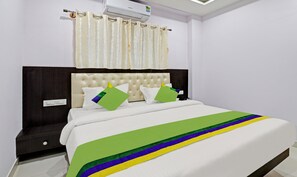 Uma cama bem arrumada com um cobertor listrado em verde e amarelo, um painel de cabeceira estofado e almofadas brancas.