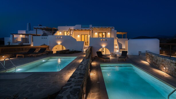 Uma villa moderna com área de piscina, espaço para sentar ao ar livre e escadaria que leva à entrada.