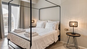 Um quarto moderno com uma cama de dossel, uma pequena mesa de cabeceira com abajur e vista para o exterior através de uma grande janela.
