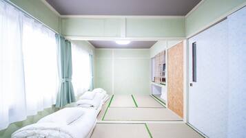 Quarto de hotel com uma cama, uma mesinha, janela com cortinas e um guarda-roupa.