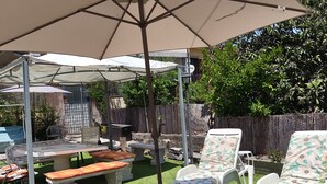 Uma área de pátio com pérgola, móveis de exterior e uma mesa de pedra.