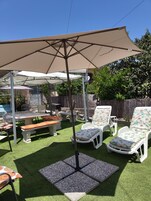Uma área de pátio com pérgola, móveis de exterior e uma mesa de pedra.