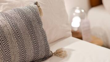 Um close-up de um travesseiro estampado com um pompom numa cama.