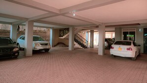 Área de estacionamento coberta com vários carros, uma escadaria e vista para o exterior.
